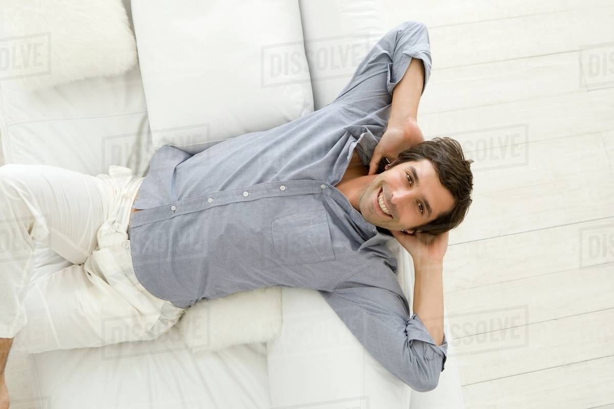 Smiling man relaxing on sofa - Stock Photo - Dissolve