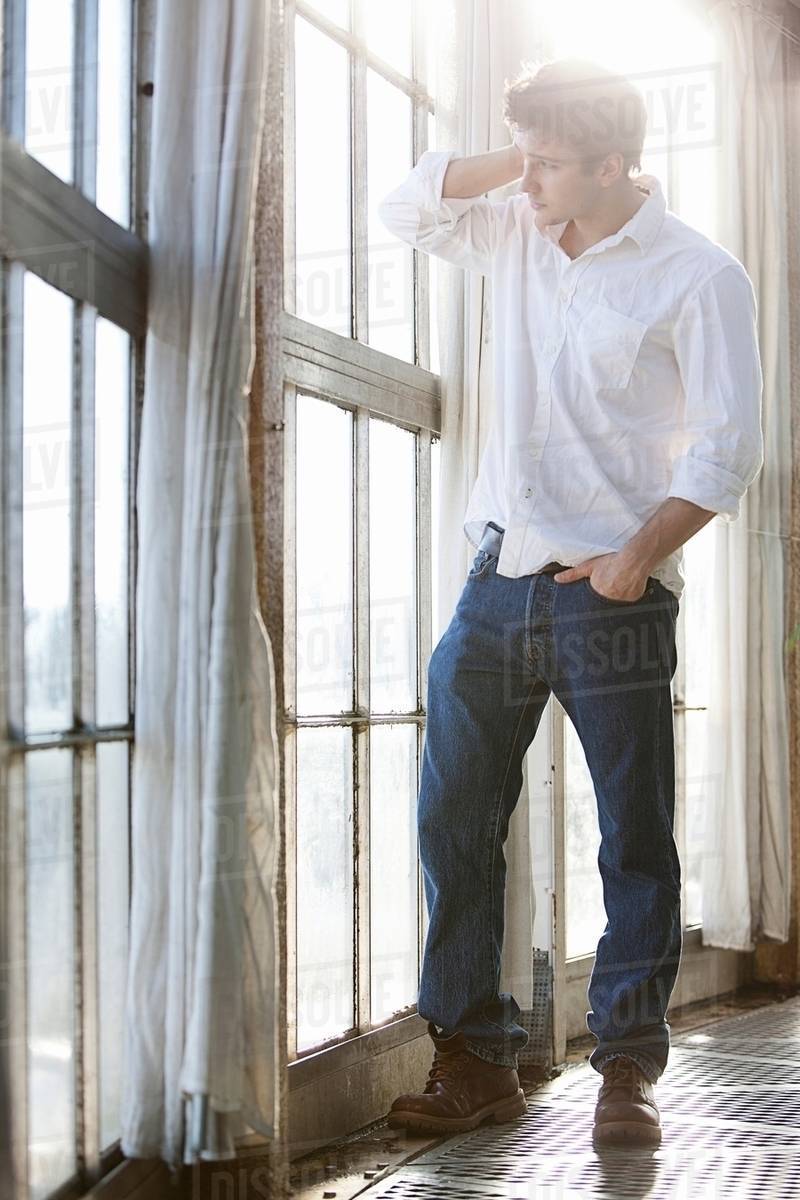 Man standing at window - Stock Photo - Dissolve