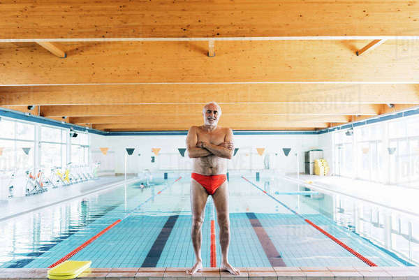 Senior man standing by swimming pool - Royalty-free Stock Photo | Dissolve