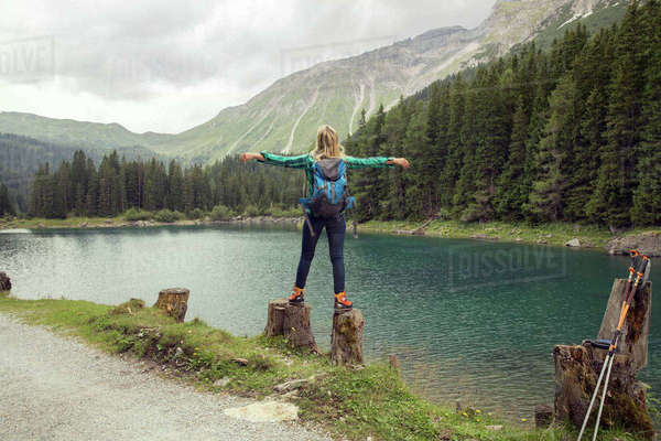 Rear view of woman balancing on rocks by lake, Tirol, Steiermark ...