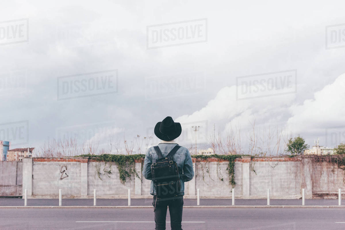 Young man standing, looking across road, rear view - Royalty-free Stock ...