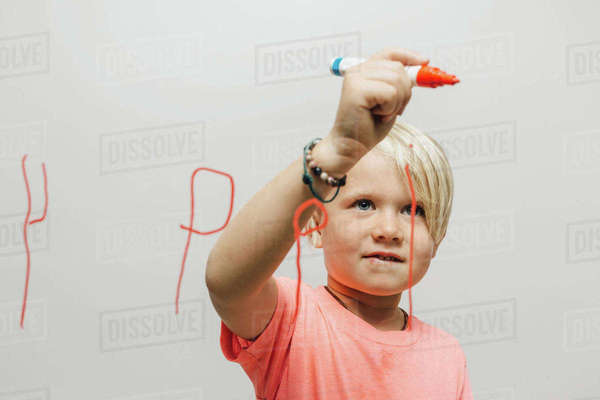 Boy writing reversed letter P onto glass wall - Stock Photo - Dissolve