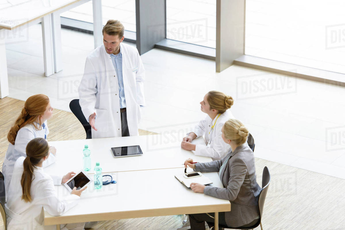 Group of doctors sitting at table, having meeting, elevated view ...