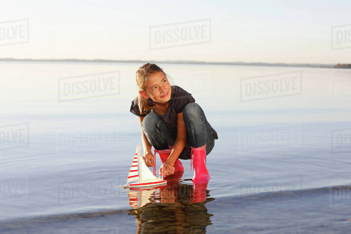 Young girl floating toy boat on water - Stock Photo - Dissolve