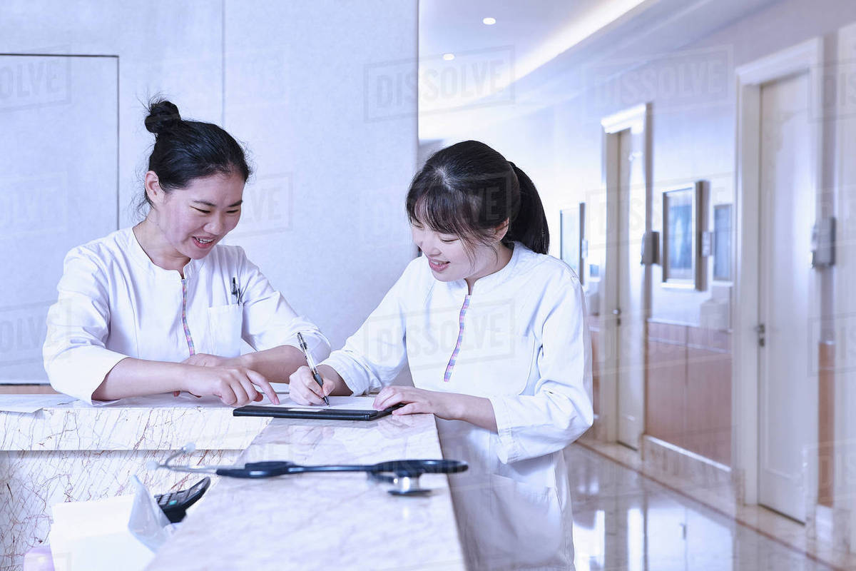 Medical professionals at hospital reception desk using digital tablet ...