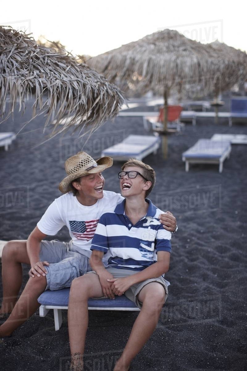 Brothers laughing together on beach - Stock Photo - Dissolve