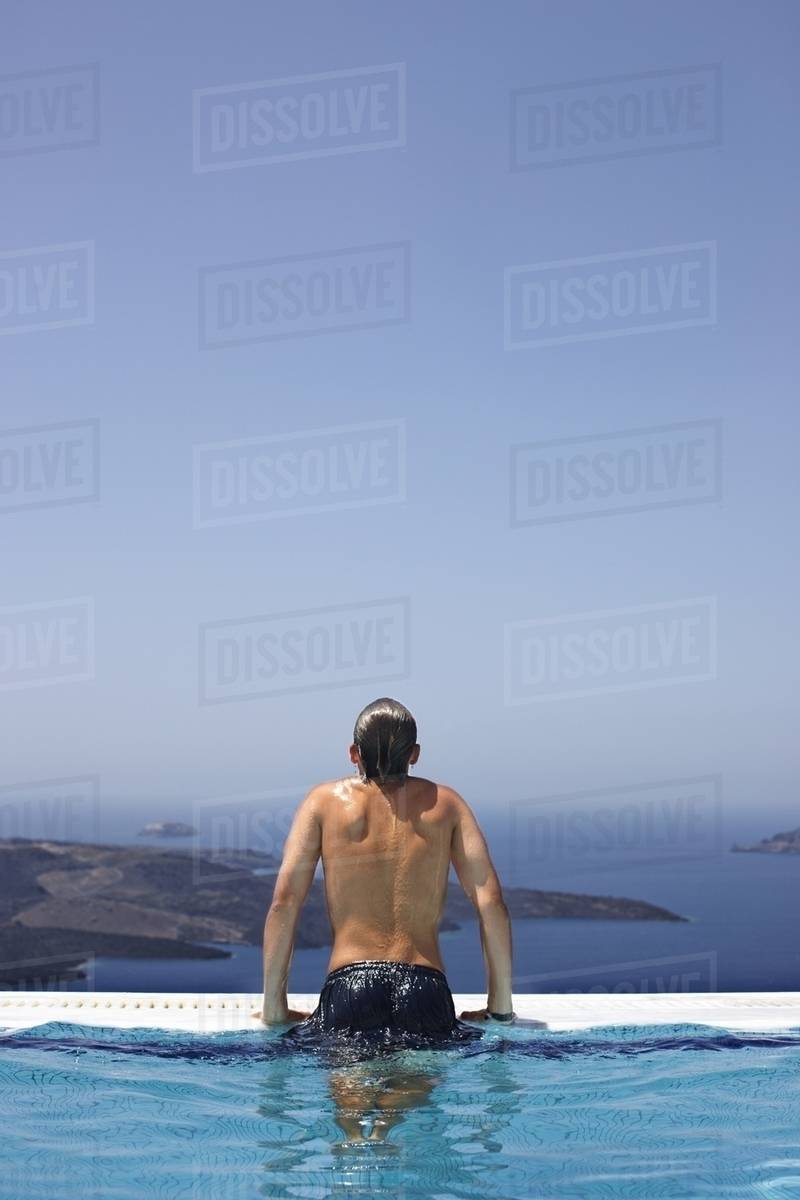 Man climbing out of infinity pool - Stock Photo - Dissolve