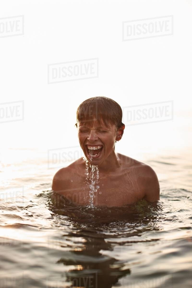 Teenage boy playing in water - Royalty-free Stock Photo | Dissolve