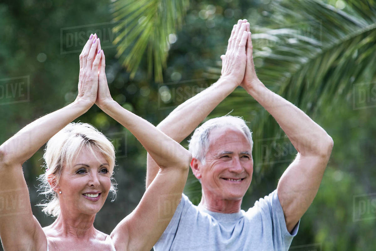 Couple, hands together, arms raised in yoga position - Stock Photo ...