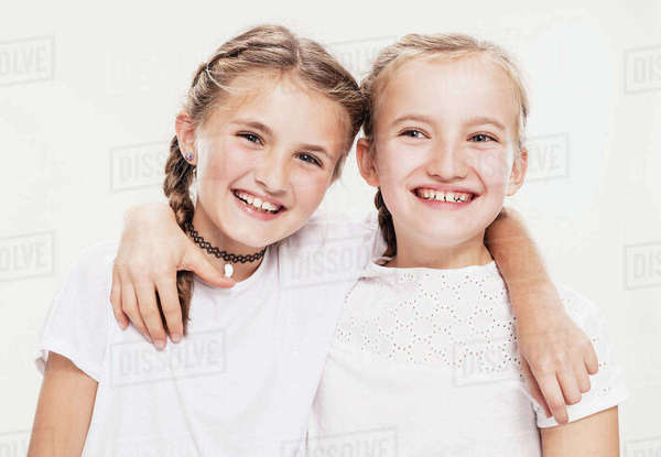 Studio portrait of two girls with arms around each other, head and ...