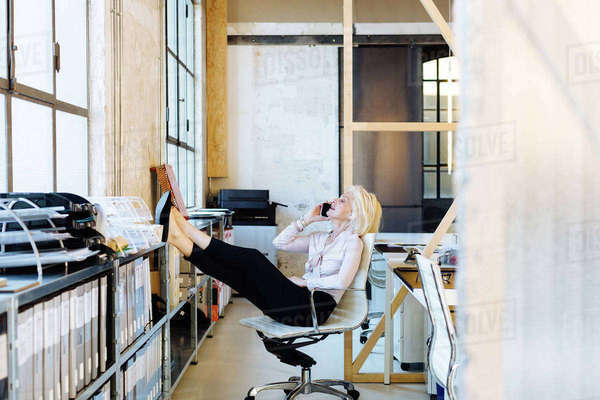 Architect using mobile phone with legs propped up - Stock Photo - Dissolve