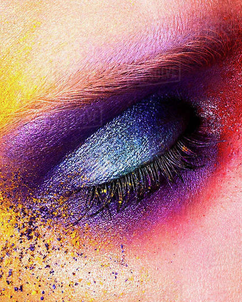 Studio shot of young woman's eye with multi coloured powder eye shadow ...