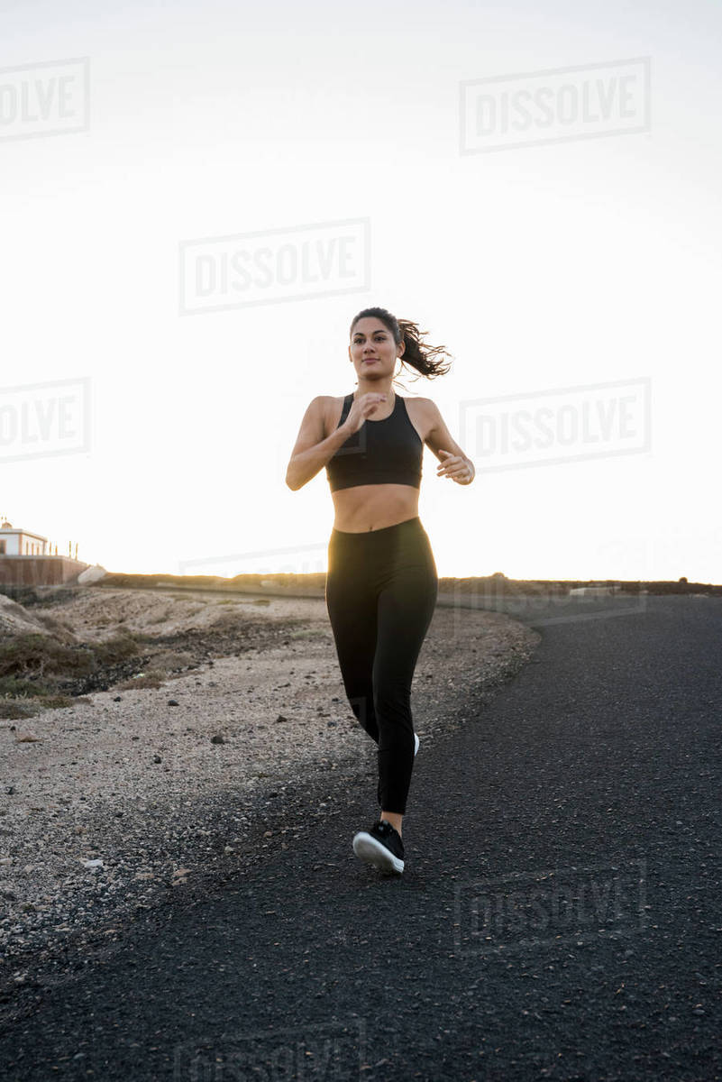 Young female runner running down rural road - Royalty-free Stock Photo ...