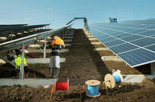 Engineers connecting solar panels on new solar farm, situated on former ...