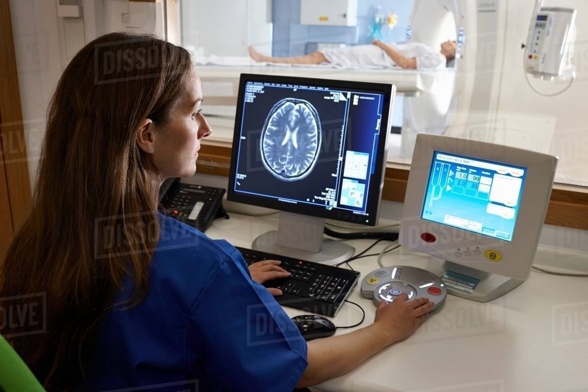 Radiologist looking at brain scan image on computer screen - Stock ...