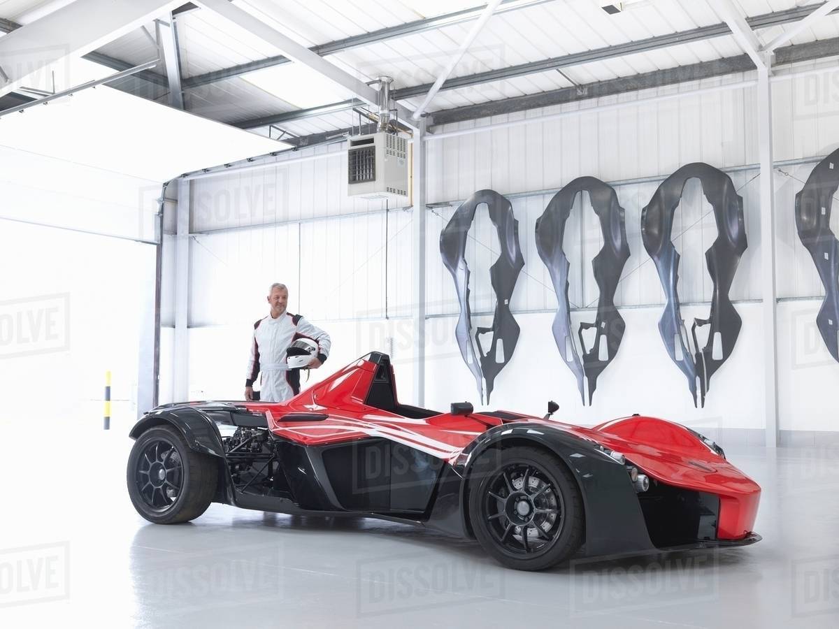 Racing driver with supercar in factory with carbon fibre car body ...
