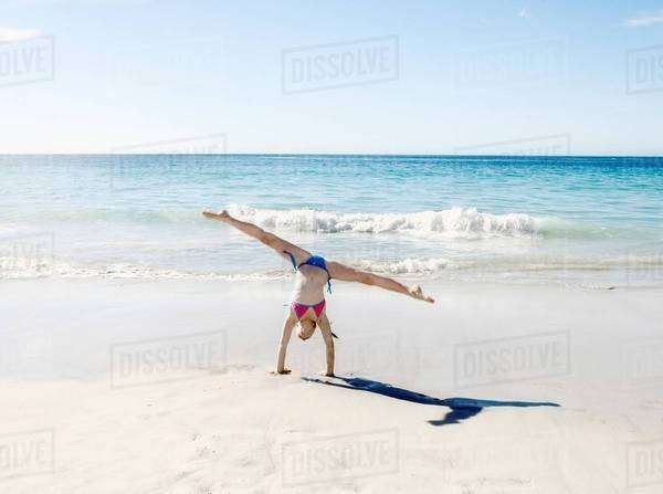 Girl doing handstand and splits on beach - Stock Photo - Dissolve