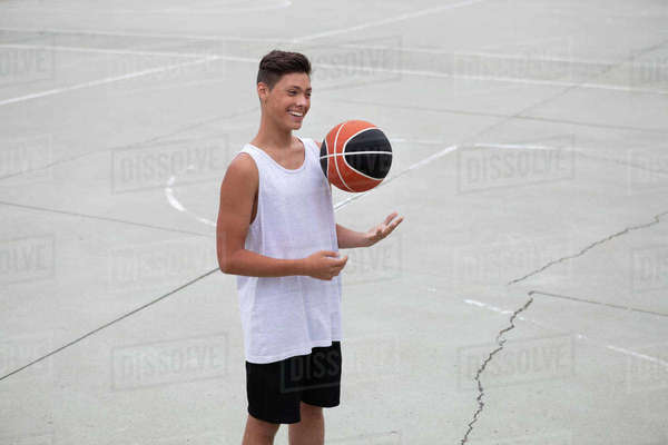 Male teenage basketball player on basketball court throwing and ...