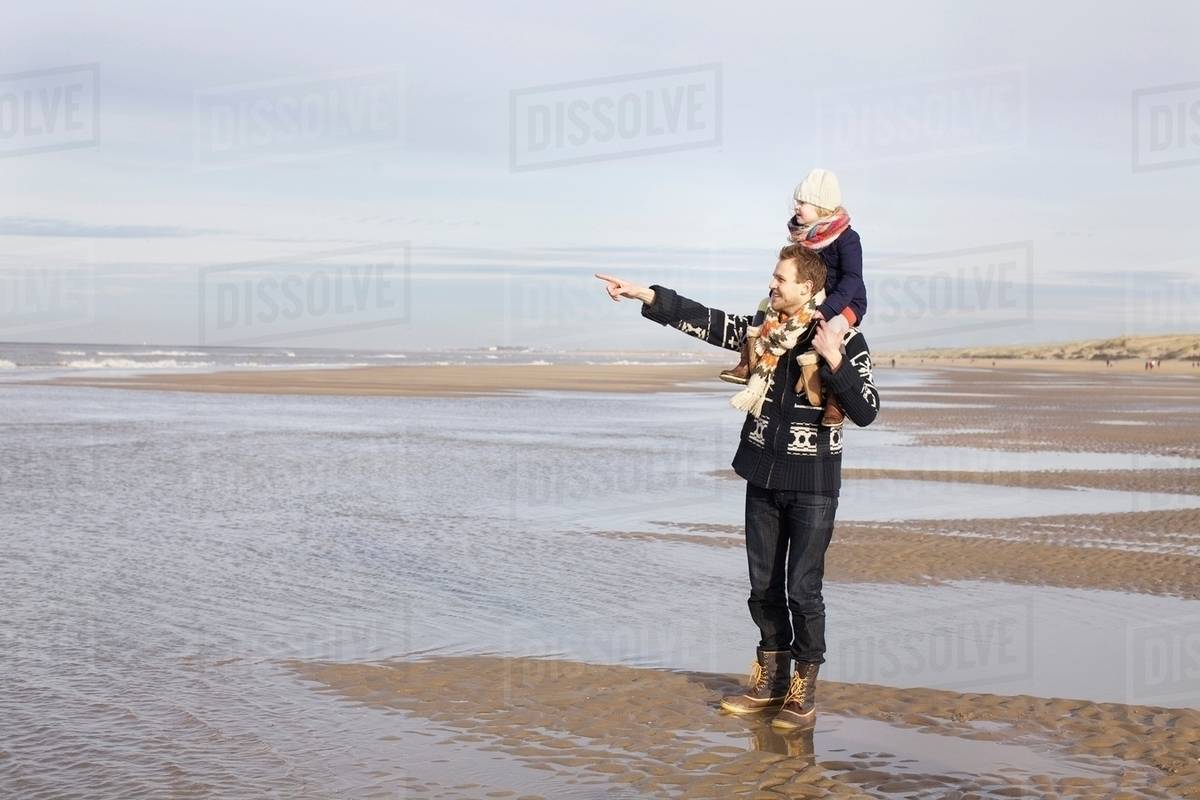 Mid adult man giving daughter shoulder ride on beach, Bloemendaal aan ...