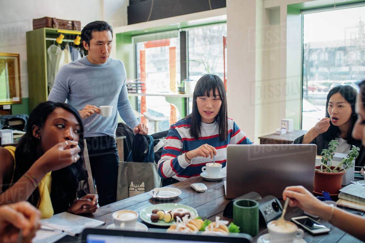 Young male and female business team sharing working lunch at cafe table ...