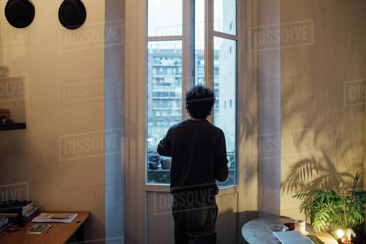 Man looking out of house window - Stock Photo - Dissolve