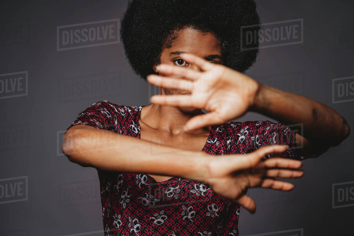 Young woman with afro hair covering face with hands, grey background ...