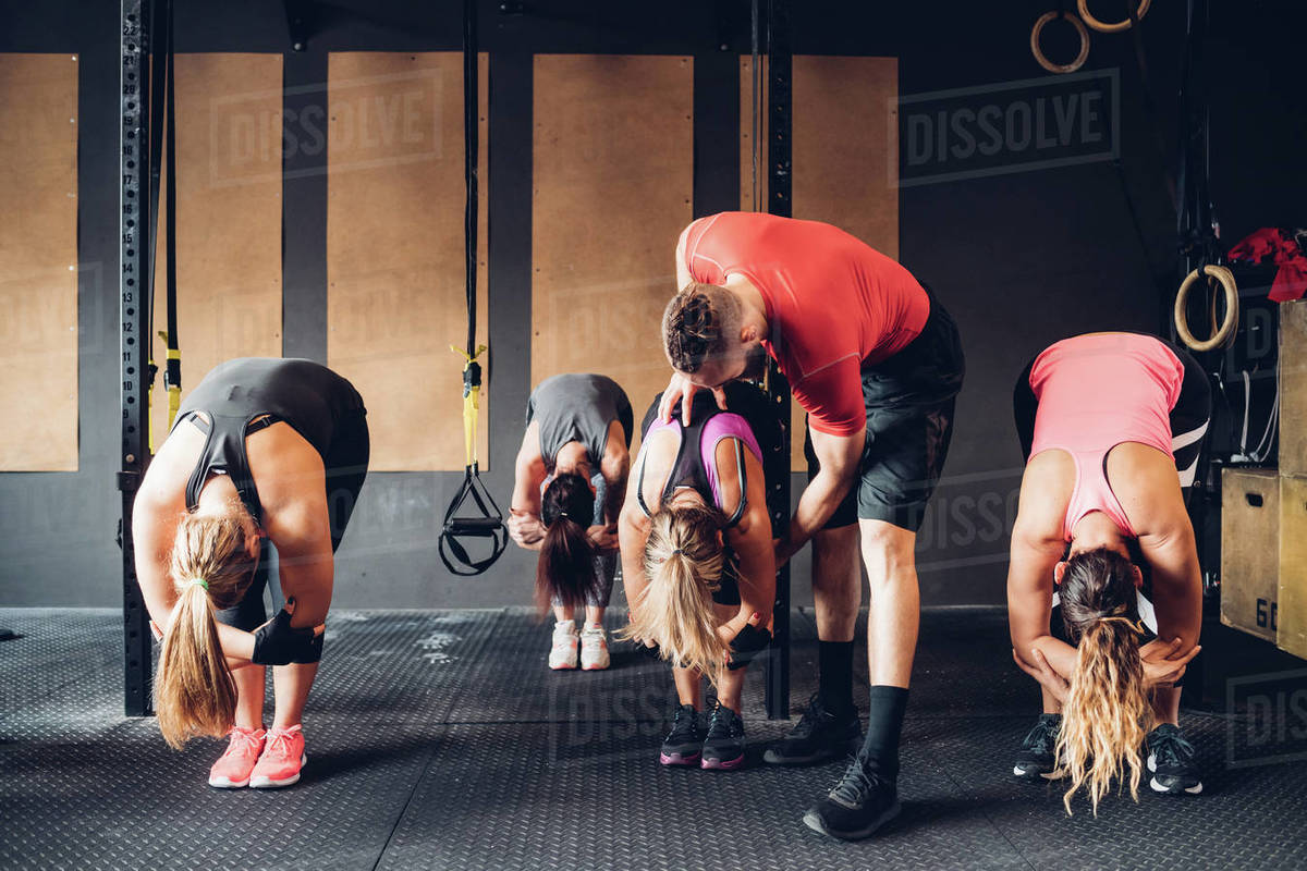 Women training in gym with male trainer, bending forward - Royalty-free ...