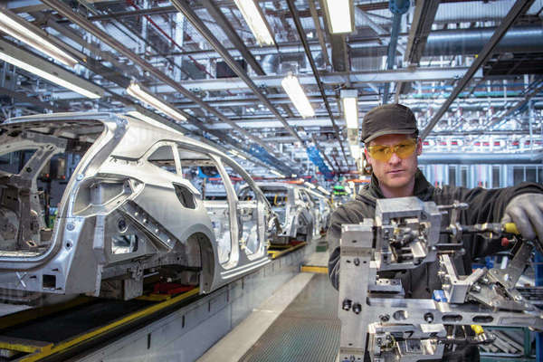 Car worker fitting parts on production line in car factory - Stock ...