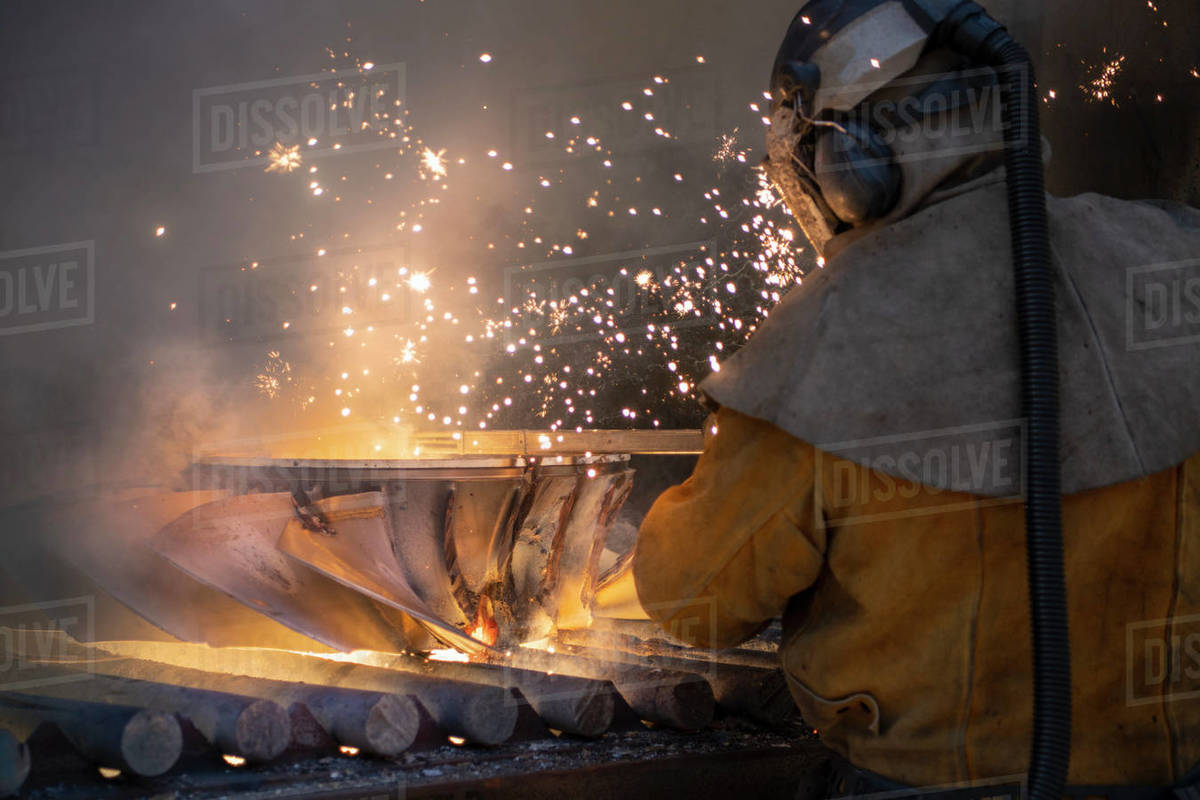Worker cutting up scrap titanium aircraft parts in titanium recycling ...