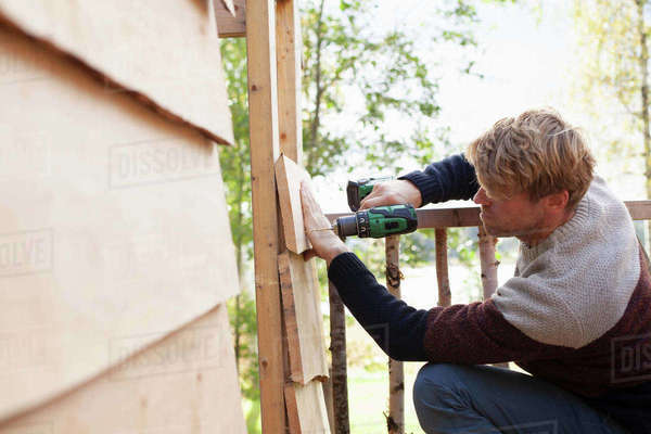 Man building treehouse in garden - Royalty-free Stock Photo | Dissolve