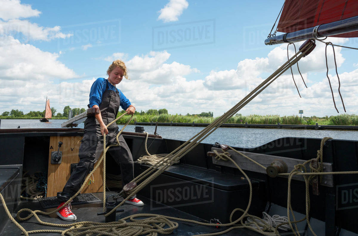 Girl stands at helm of large flat-bottom traditional sailing ship ...