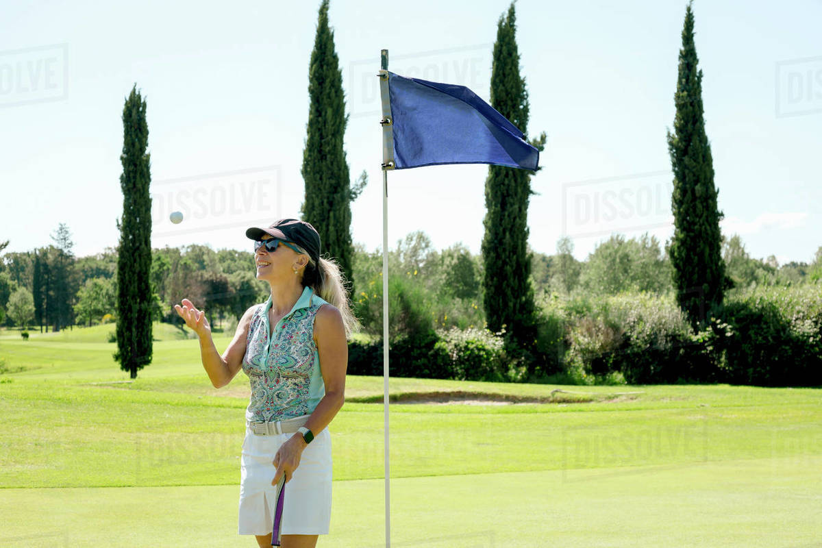 Woman playing golf on golf course - Stock Photo - Dissolve