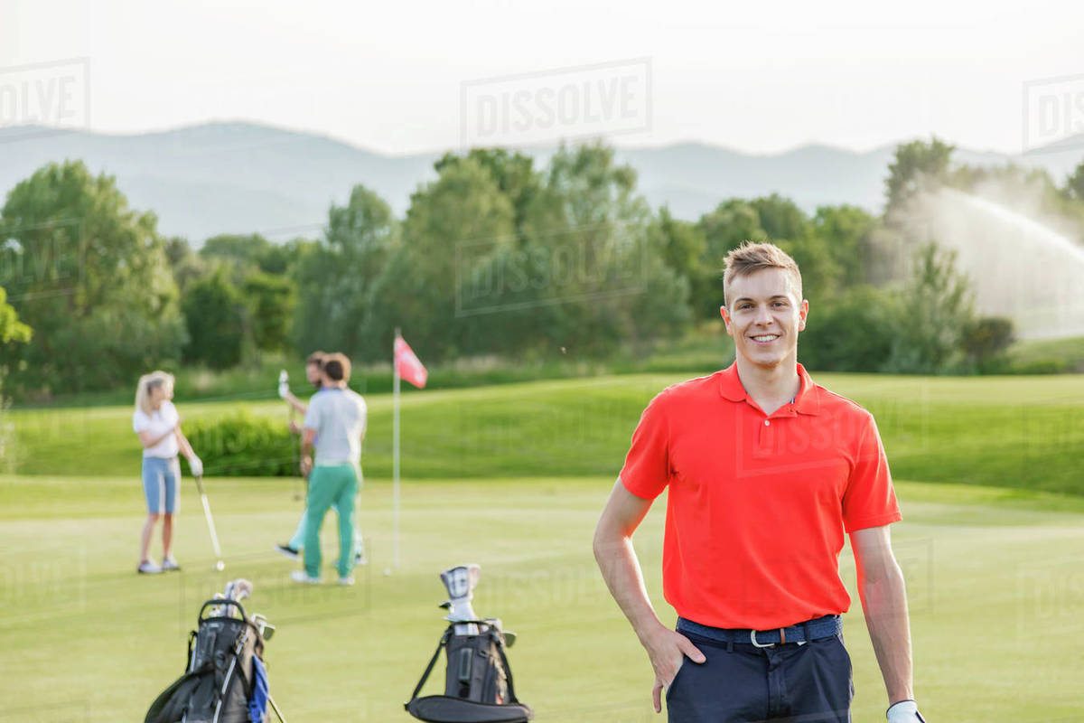 Man with friends playing golf on golf course in background - Stock ...
