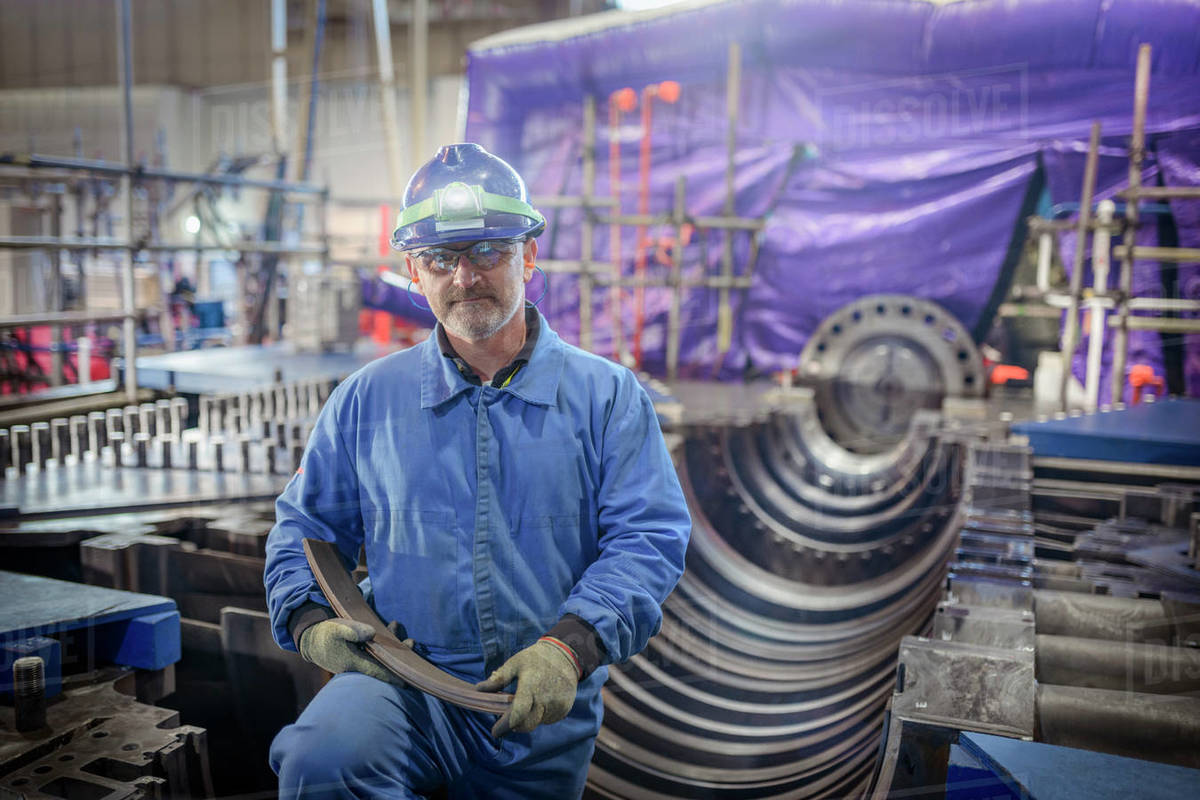Engineer standing beside a turbine in a nuclear power station ...