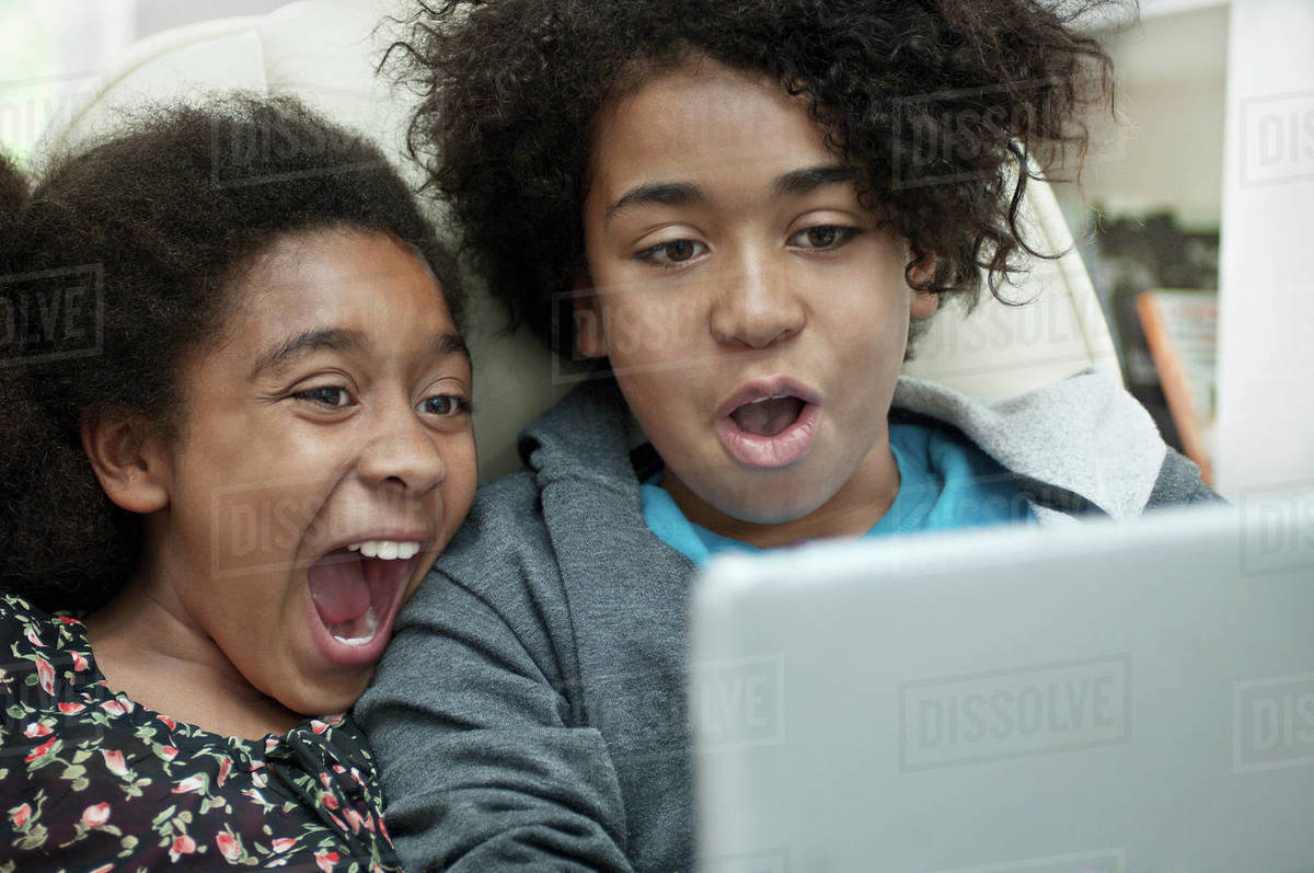 Two children online, sharing a laptop computer laughing. - Stock Photo ...