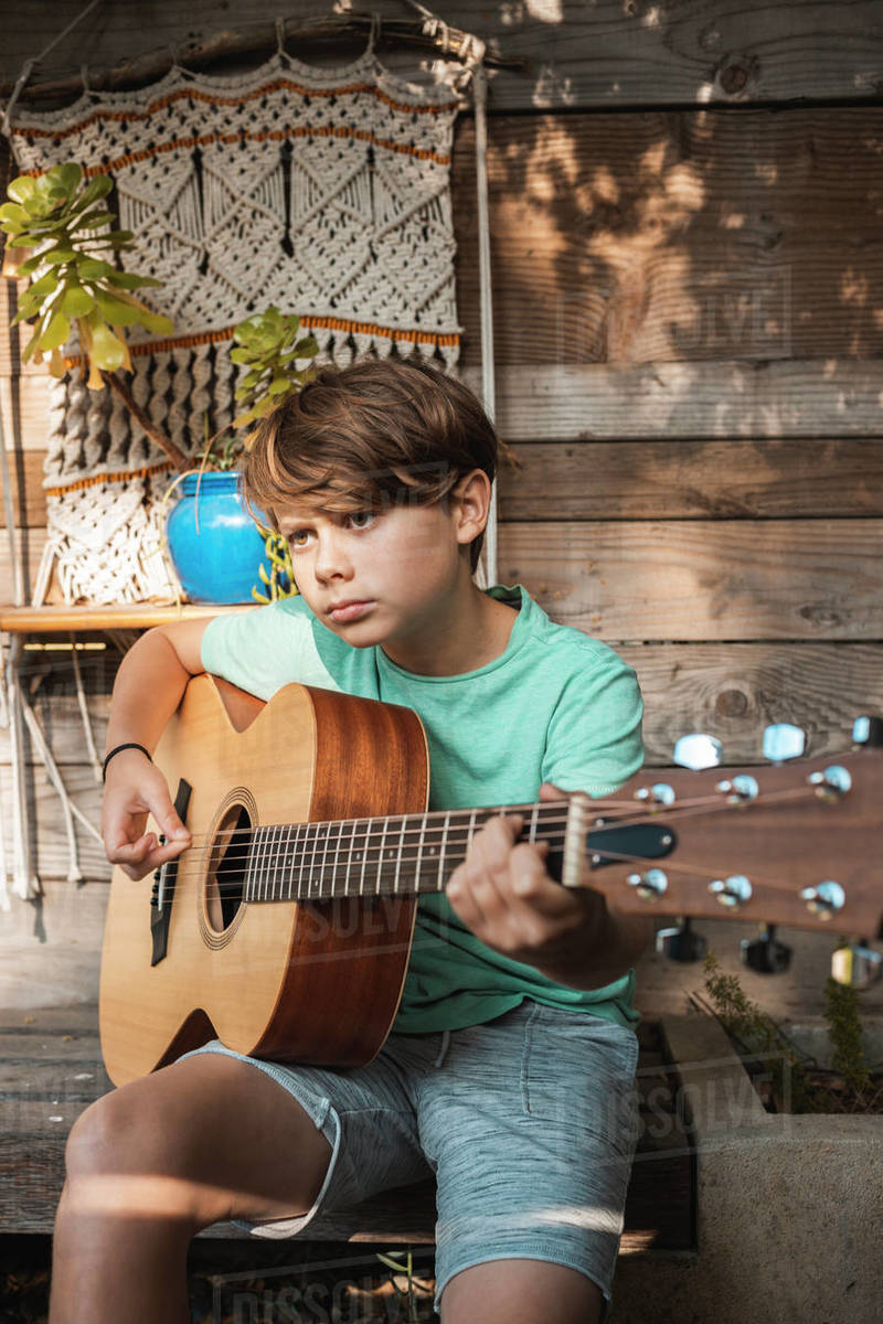 Portrait of brown haired boy playing guitar. - Stock Photo - Dissolve