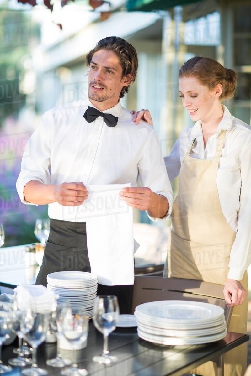 Waiter and waitress setting up tables in patio restaurant - Royalty ...