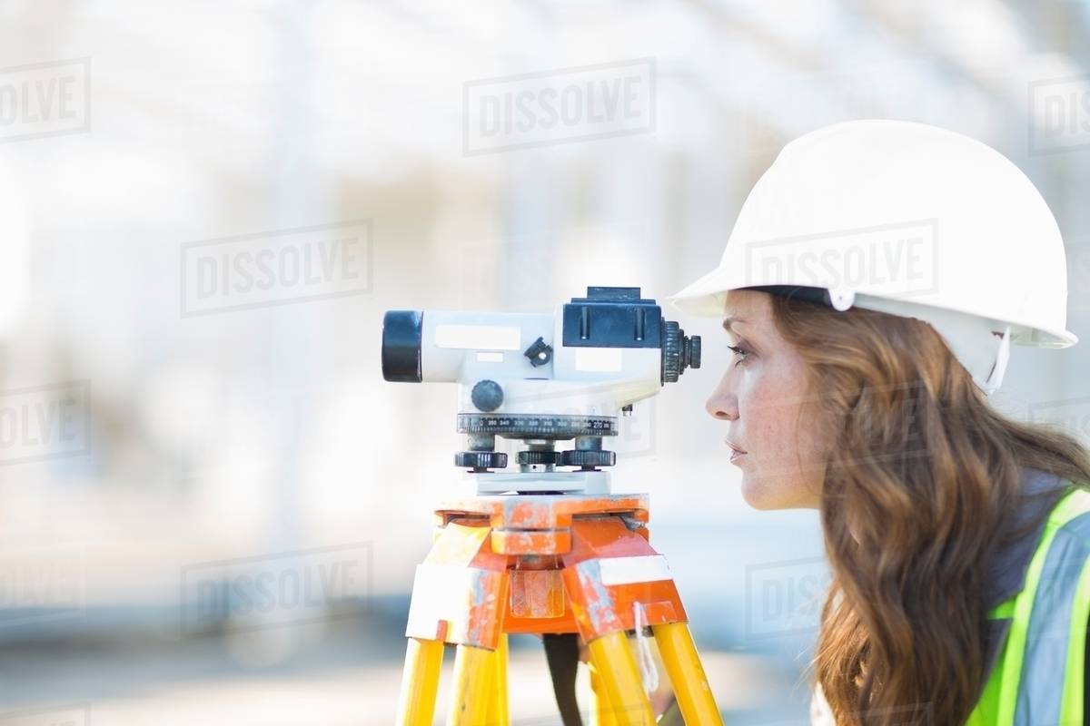 Female surveyor looking through level on construction site - Stock ...