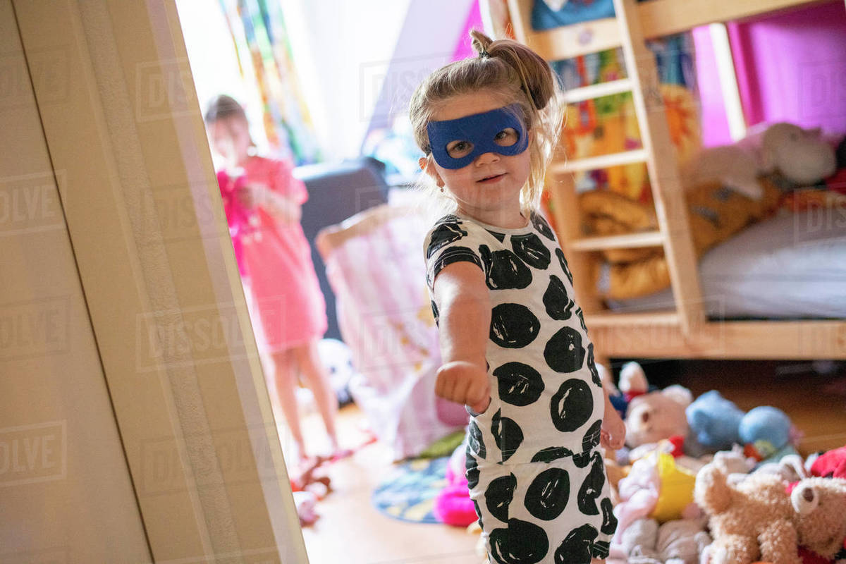 Young girl in costume playing superhero dressing up with her sister in ...