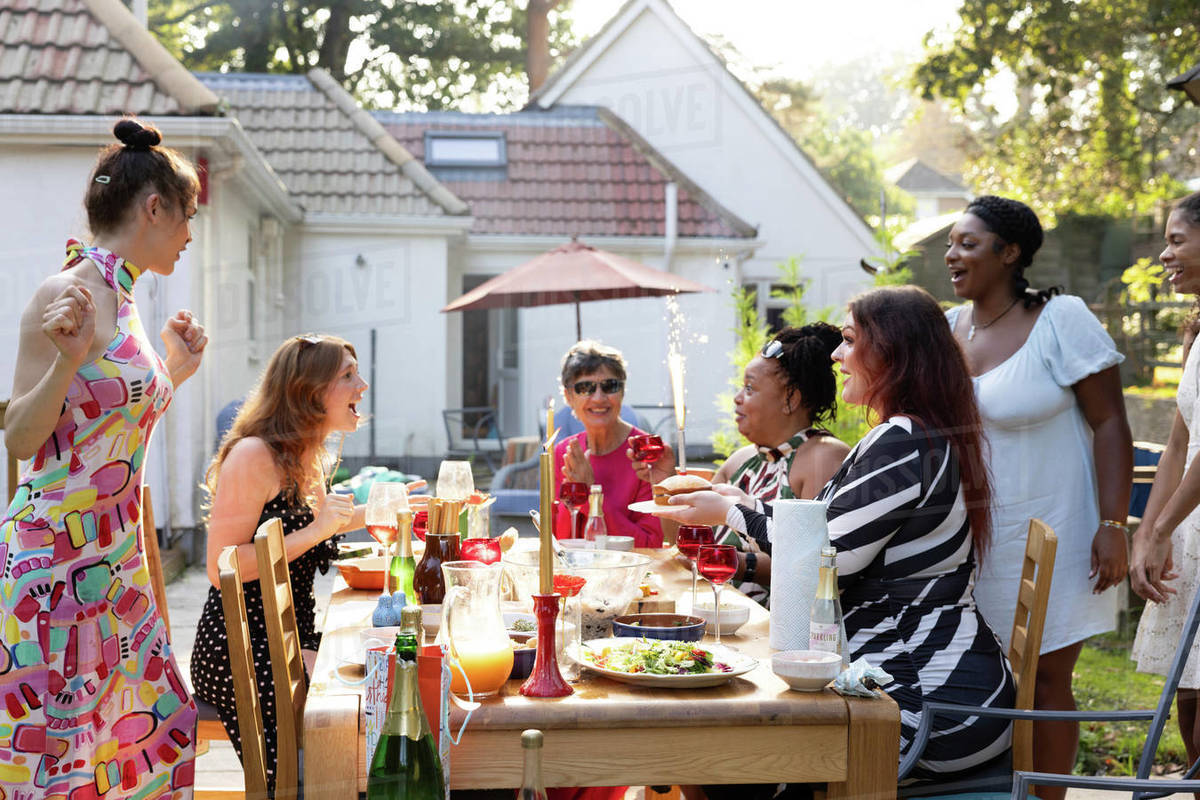 A mixed gathering of women laughing and having fun at a summer garden ...