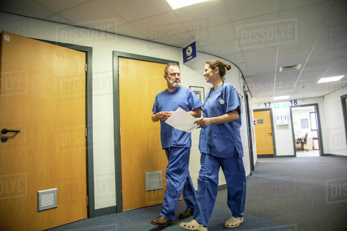Two healthcare workers walking in a hospital corridor, medical practice ...