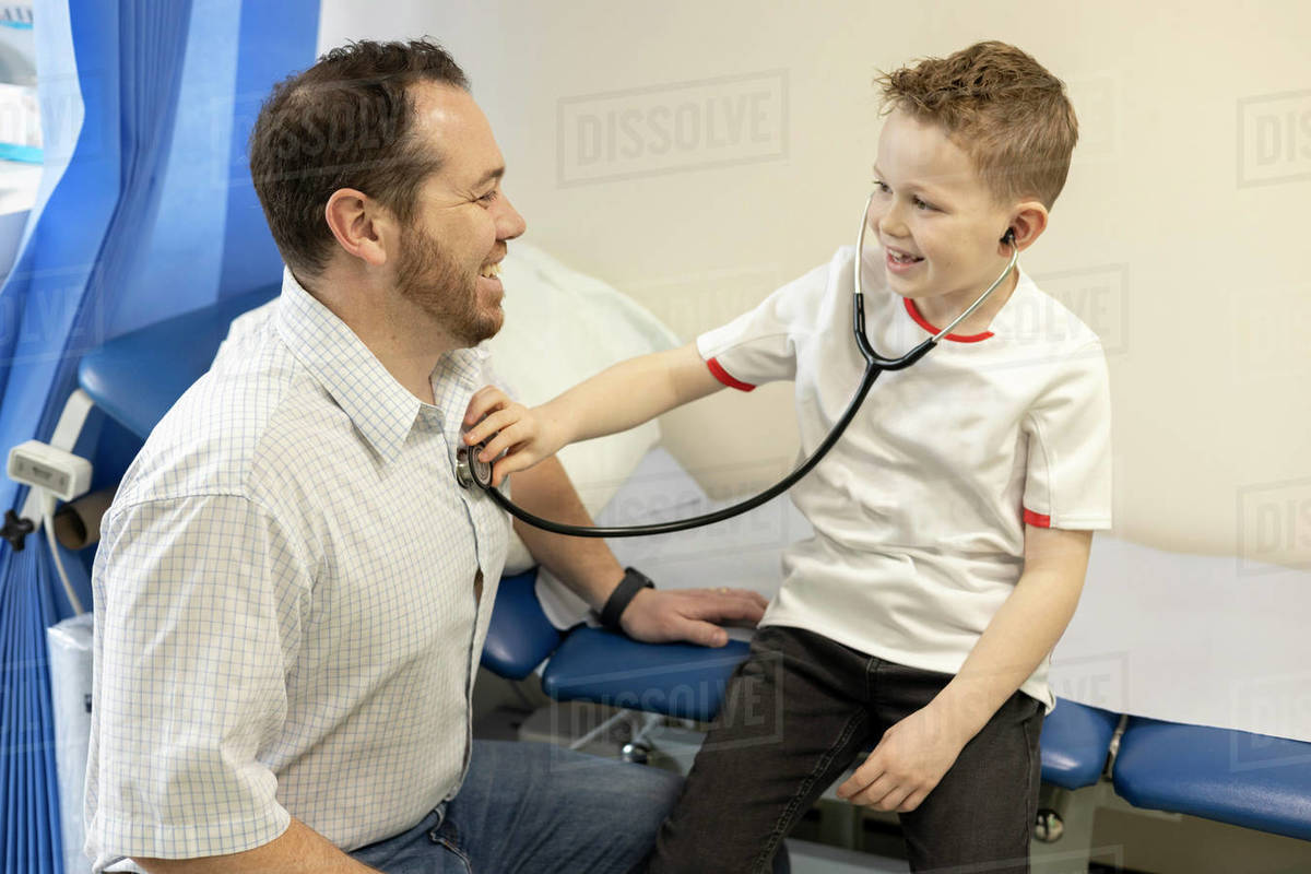 Boy using stethoscope on doctor for fun - Stock Photo - Dissolve