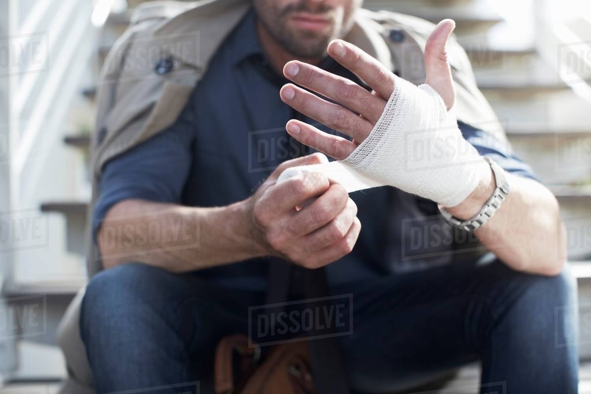 Man bandaging hand on staircase - Stock Photo - Dissolve