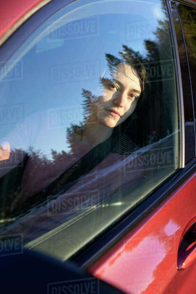 A person is looking through a car window, with their face partially ...