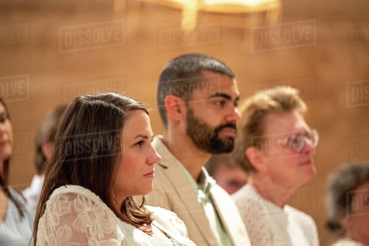 A group of attentive guests at a formal event with a focus on a man and ...