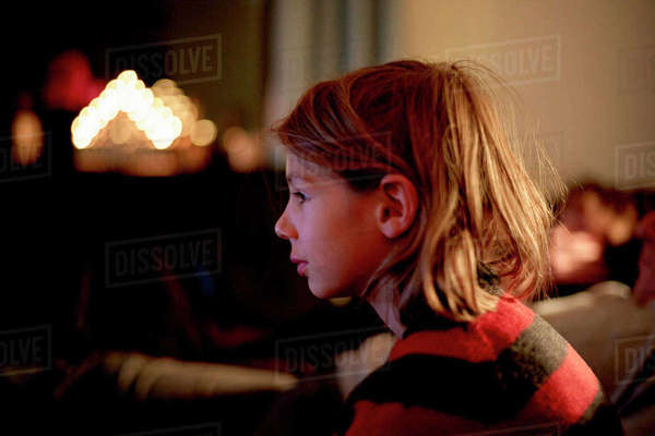 Side profile of a young girl focused on a glowing light source in a ...