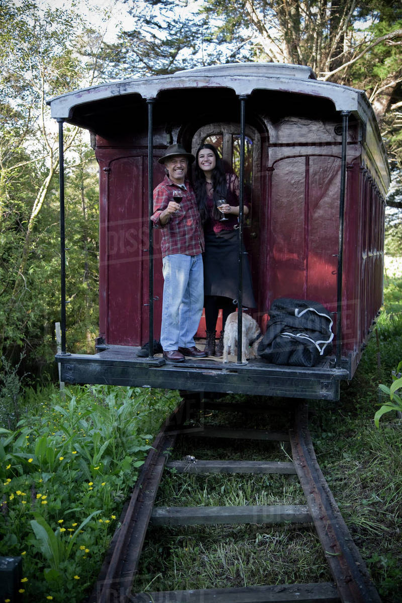 A man and a woman stand smiling in an old-fashioned railway carriage on ...