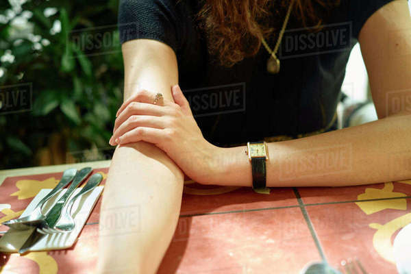 Close-up of a woman's arm resting on a restaurant table with cutlery ...