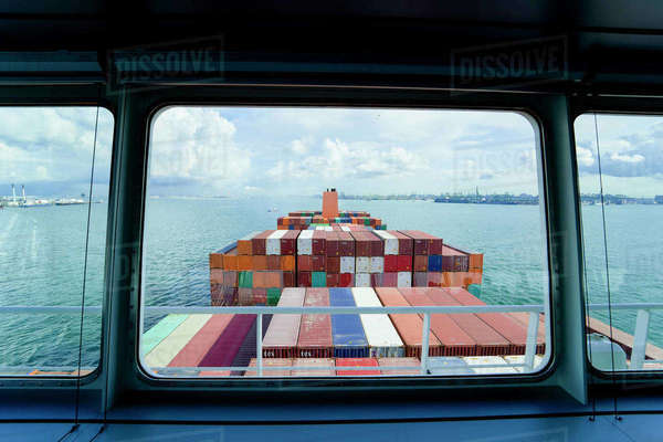 Cargo ship's navigation bridge window view showing a stack of colorful ...