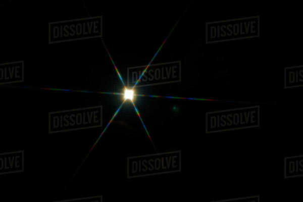 Bright starburst light effect with colorful diffraction streaks on a ...